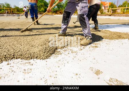 Construction worker, rigger is using rake to spreading, leveling ...