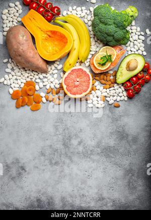 Vegetables, fruit and foods containing potassium over gray stone ...