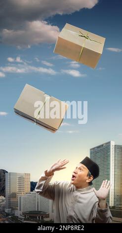 Asian Muslim man afraid of dropping box with sunset sky background ...