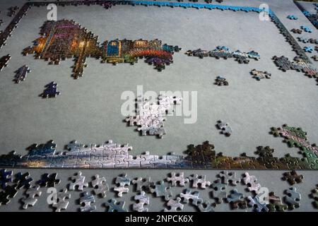 Jigsaw pieces and a partially completed jigsaw on a wooden table Stock ...