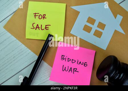 For Sale and Bidding War write on sticky notes isolated on Wooden Table ...
