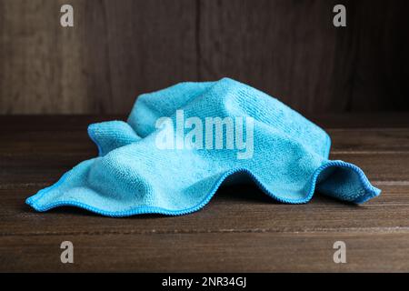 Light blue microfiber cloth on wooden table, top view. Space for text ...