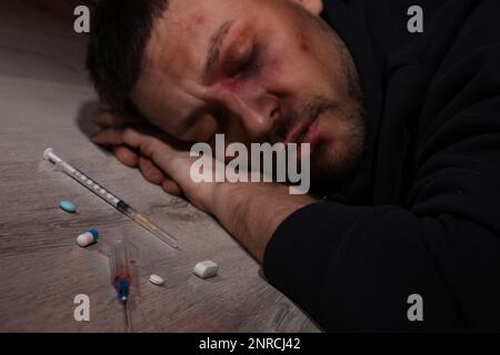 Overdosed man indoors, focus on different drugs Stock Photo - Alamy