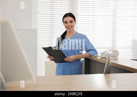 Receptionist with clipboard at countertop in hospital Stock Photo - Alamy