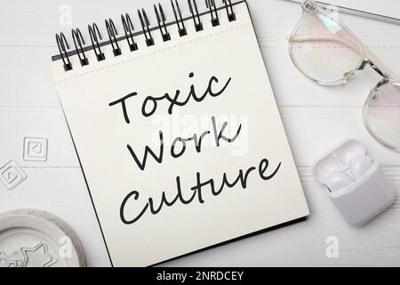 Notebook with text Toxic Work Culture and crumpled paper on grey marble ...