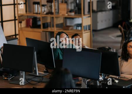 Multiracial female and male hackers discussing over computer at desk in ...