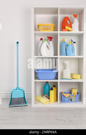 Shelving unit with detergents and cleaning tools near white wall ...