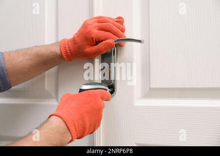 Handyman with screw gun repairing door lock indoors Stock Photo - Alamy