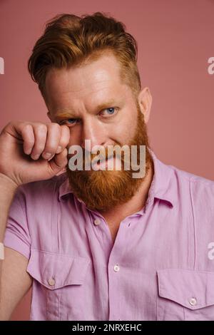 Ginger white man with beard crying while wiping his tears isolated over ...