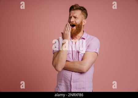 White ginger man with beard covering his mouth and looking at camera ...