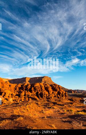 Swirling cirrus horsetail clouds over striped Cutler sandstone with ...