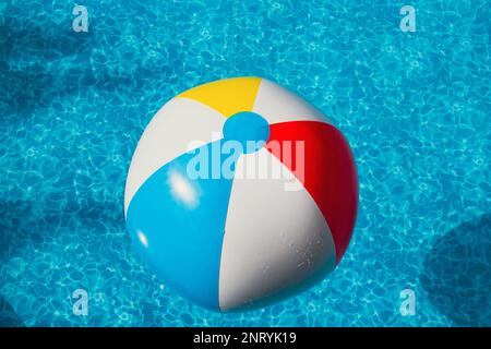 Inflatable beach ball floats in clear blue water od outdoor swimming ...