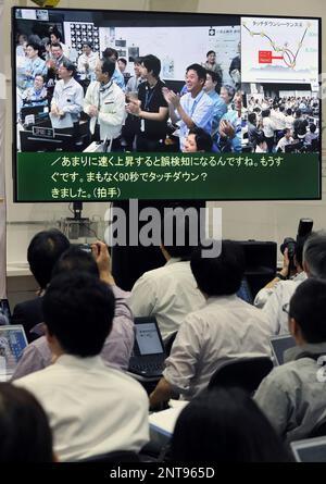 A monitor shows people at the JAXA control room celebrate as the ...