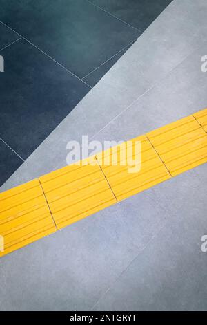 Top view of yellow tactile tiles for the blind stacked on gray tiled ...
