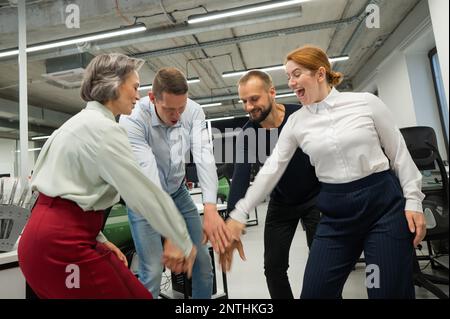Four colleagues give the low five in the office Stock Photo - Alamy