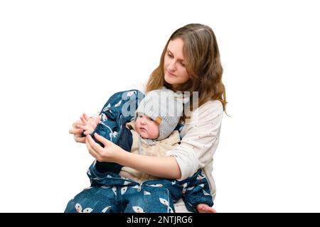 Mother puts a warm scarf on the toddler baby sitting in the home ...