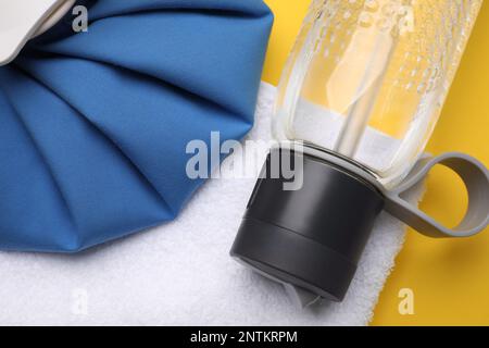Bottle of water, cold compress and towel on white background, flat lay ...