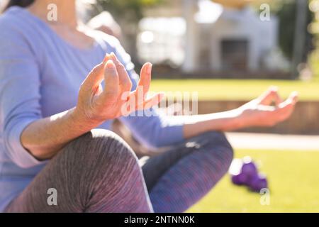 Midsection of asian senior woman meditating in prayer position in yard ...