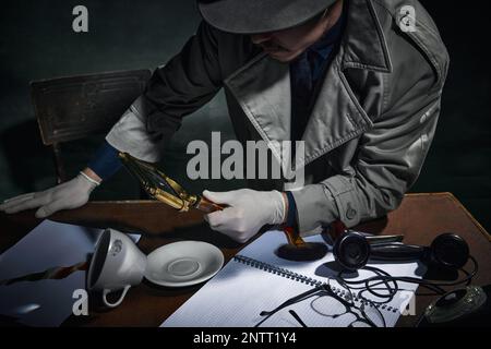 Cropped image of male detective looking in magnifying glass at ...
