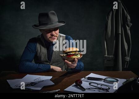 Professional detective in fedora hat sitting at table and playing ...