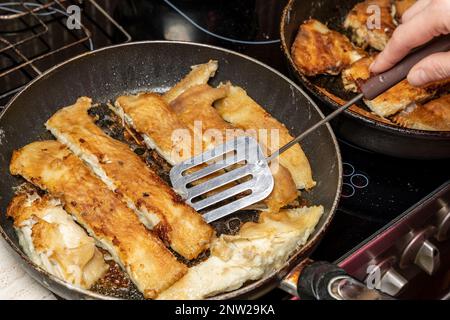 the cook checks the readiness of the fish with a fork Stock Photo - Alamy