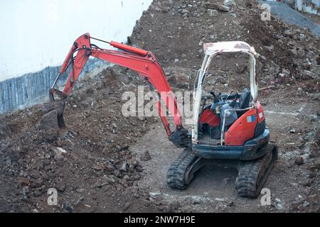 Red and white mini excavator on a construction site Stock Photo - Alamy