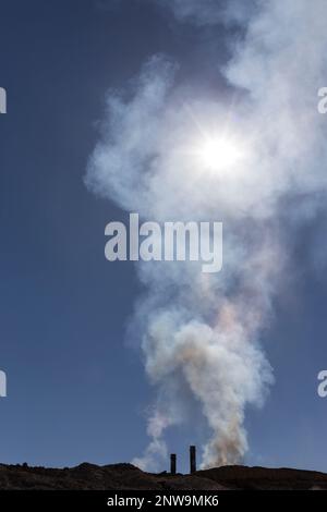 Industrial mining complex on barren land releasing toxic fumes onto a ...