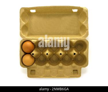 Brown open egg box on a dark table with ten white eggs in it. One egg ...