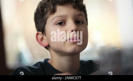 One small boy chewing food at lunch table. Candid closeup face of ...