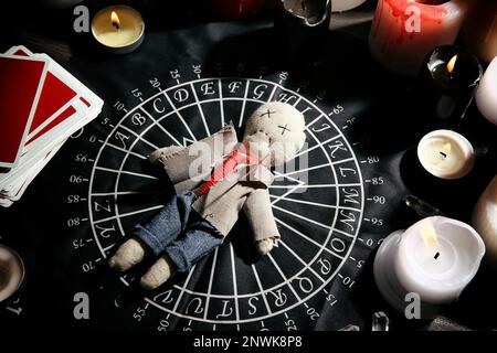 Voodoo doll pierced with needle surrounded by ceremonial items on table ...