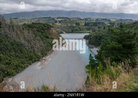 The blue water of the Rakaia river as it flows through the hilly forest ...