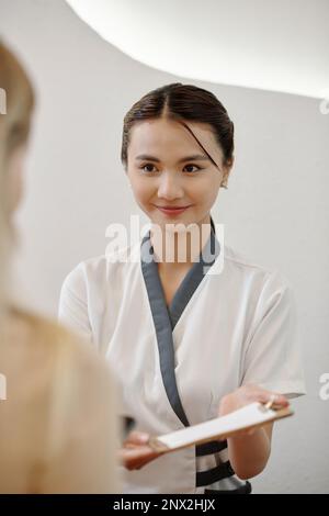 Beauty salon receptionist asking client to fill personal information ...