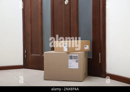 Stacked parcels near door on floor. Delivery service Stock Photo - Alamy