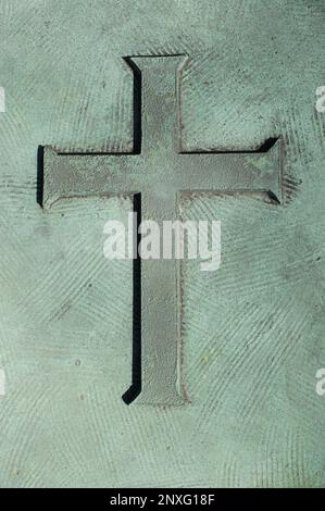 A simple typical cross embossed on a copper metal wall in a black and ...