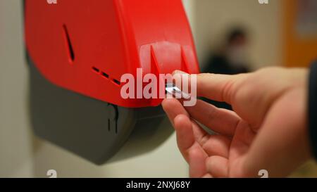 Closeup of Waiting Number Machine. Customer hand pulls a numbered ...
