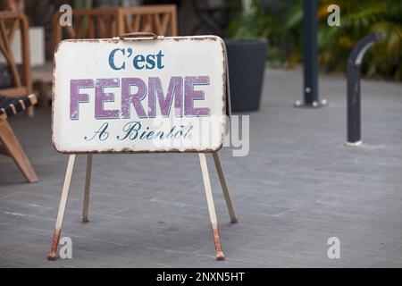 Metallic outdoor shop sign stating in french “Bienvenue, Entrez, c'est ...