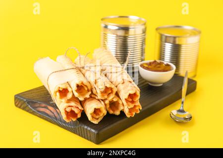 Board with stack of delicious wafer rolls tied by string on grey ...