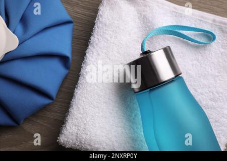 Bottle of water, cold compress and towel on light blue background, flat ...