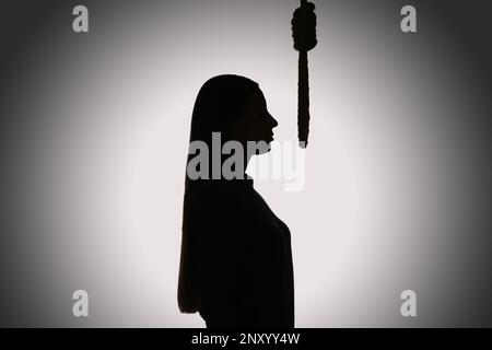 Silhouette of woman with rope noose on neck against light background ...