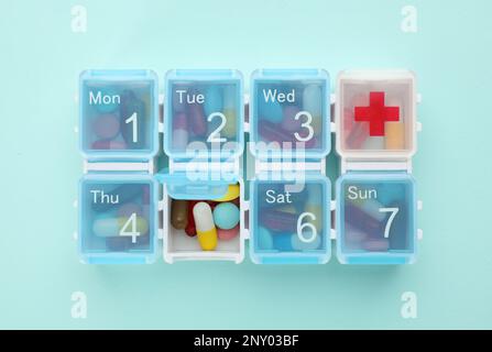 Pill box with medicaments on turquoise background, top view. Space for ...