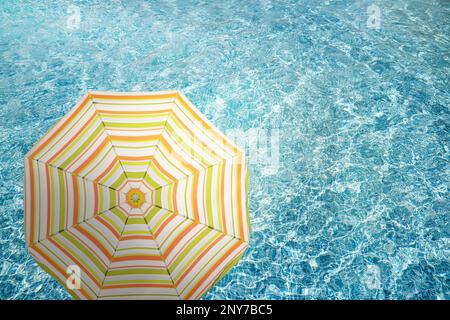 Open beach umbrella and swimming pool. Summer vacation Stock Photo - Alamy