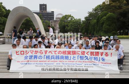 People including atomic-bomb victim sit and hold a banner to protest ...
