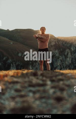 A man stretching his arms after a hard workout in the early hours of ...