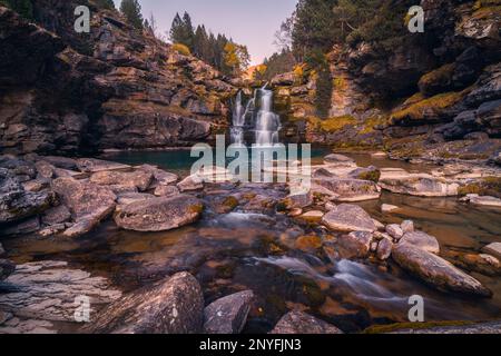 Amazing view of rapid waterfall flowing through rocky cliffs in autumn ...
