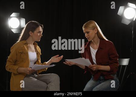 Professional actresses reading their scripts during rehearsal in ...