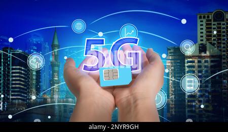 Woman demonstrating 5G SIM card model and cityscape with connection ...