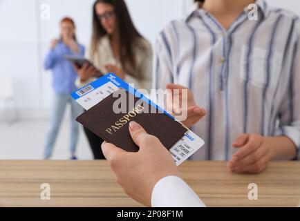 Agent giving passport with ticket to client at check-in desk in airport ...