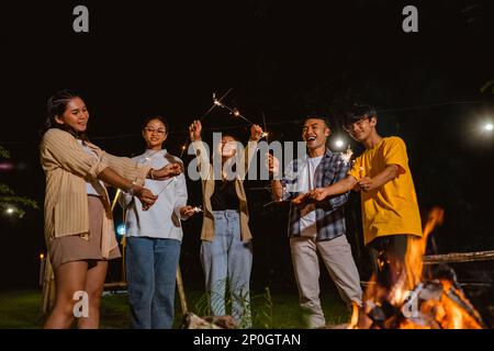 a group of people playing fireworks happily and put its together Stock ...