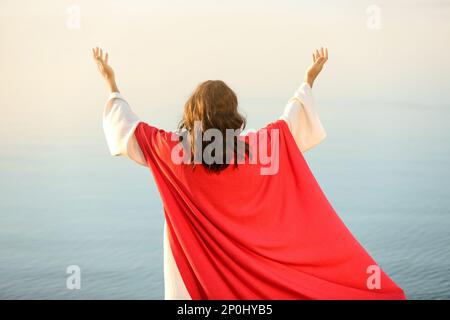 Jesus Christ raising hands near water outdoors, back view Stock Photo ...
