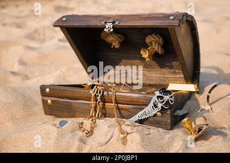 Open wooden chest with treasures on sand Stock Photo - Alamy